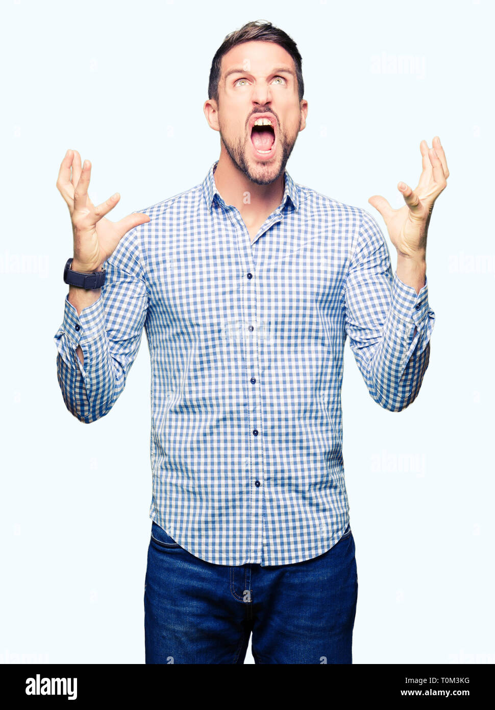Handsome business man with blue eyes crazy and mad shouting and yelling ...
