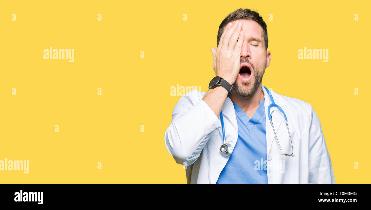 Handsome doctor man wearing medical uniform over isolated background ...