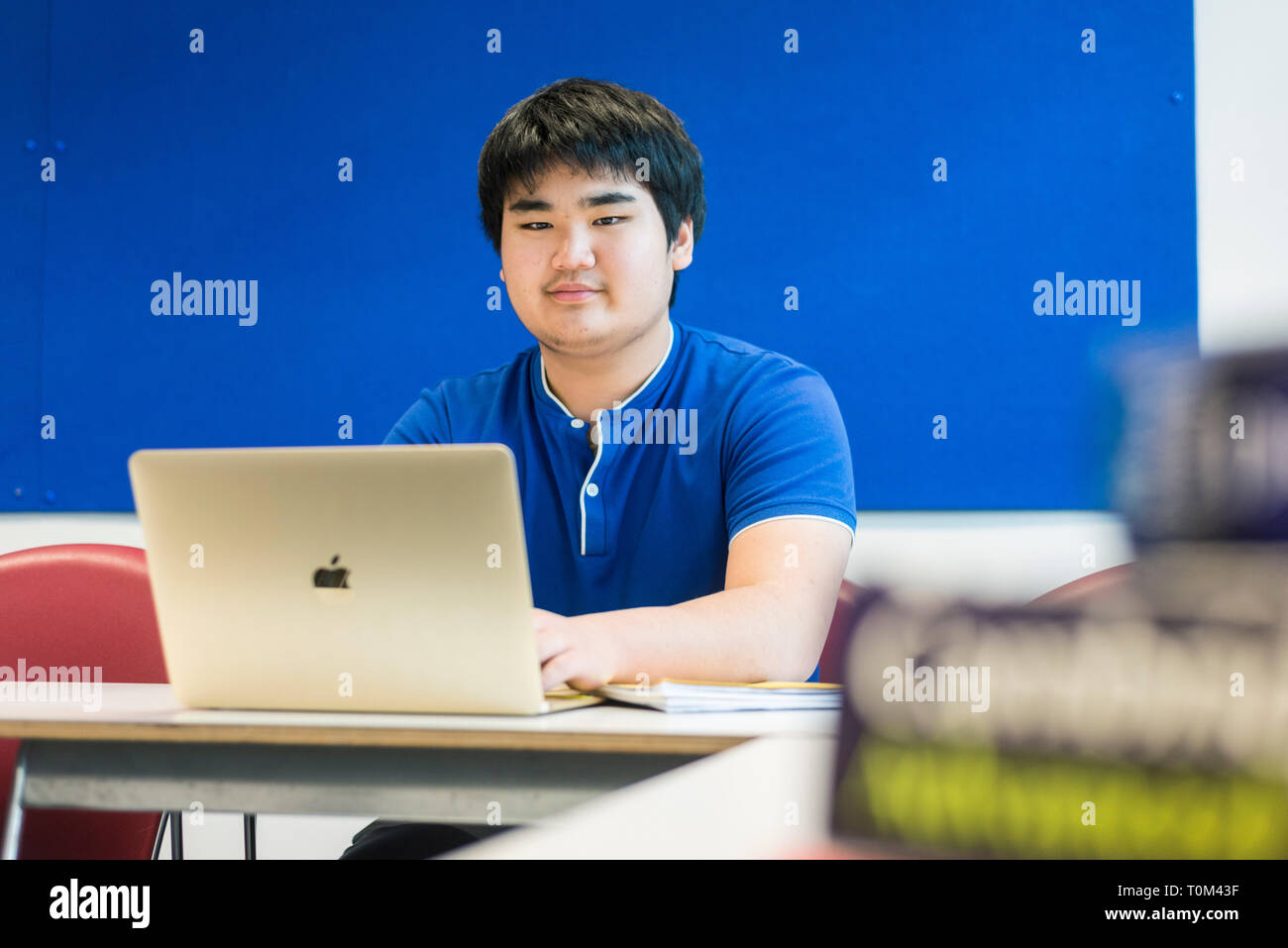 An international asian young male student sits in a classroom at a desk ...