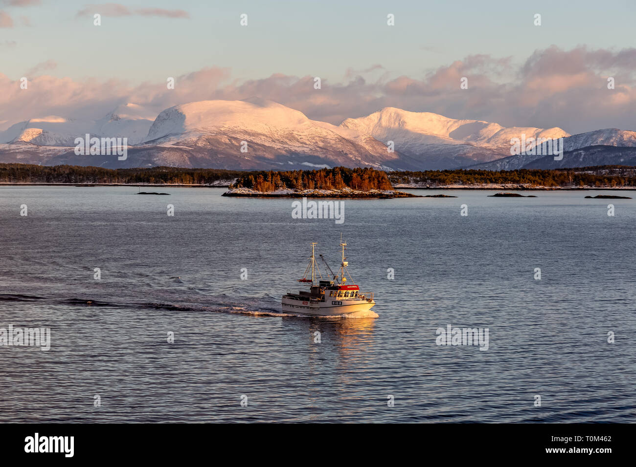 A small fishing boat approaching the port of Molde in Norway, in low ...