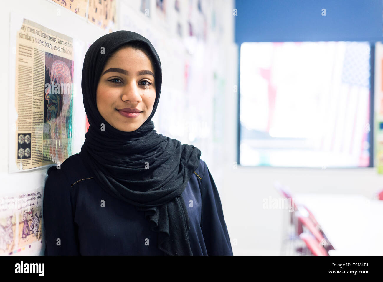 A young Muslim international student stands in the hallways on campus ...