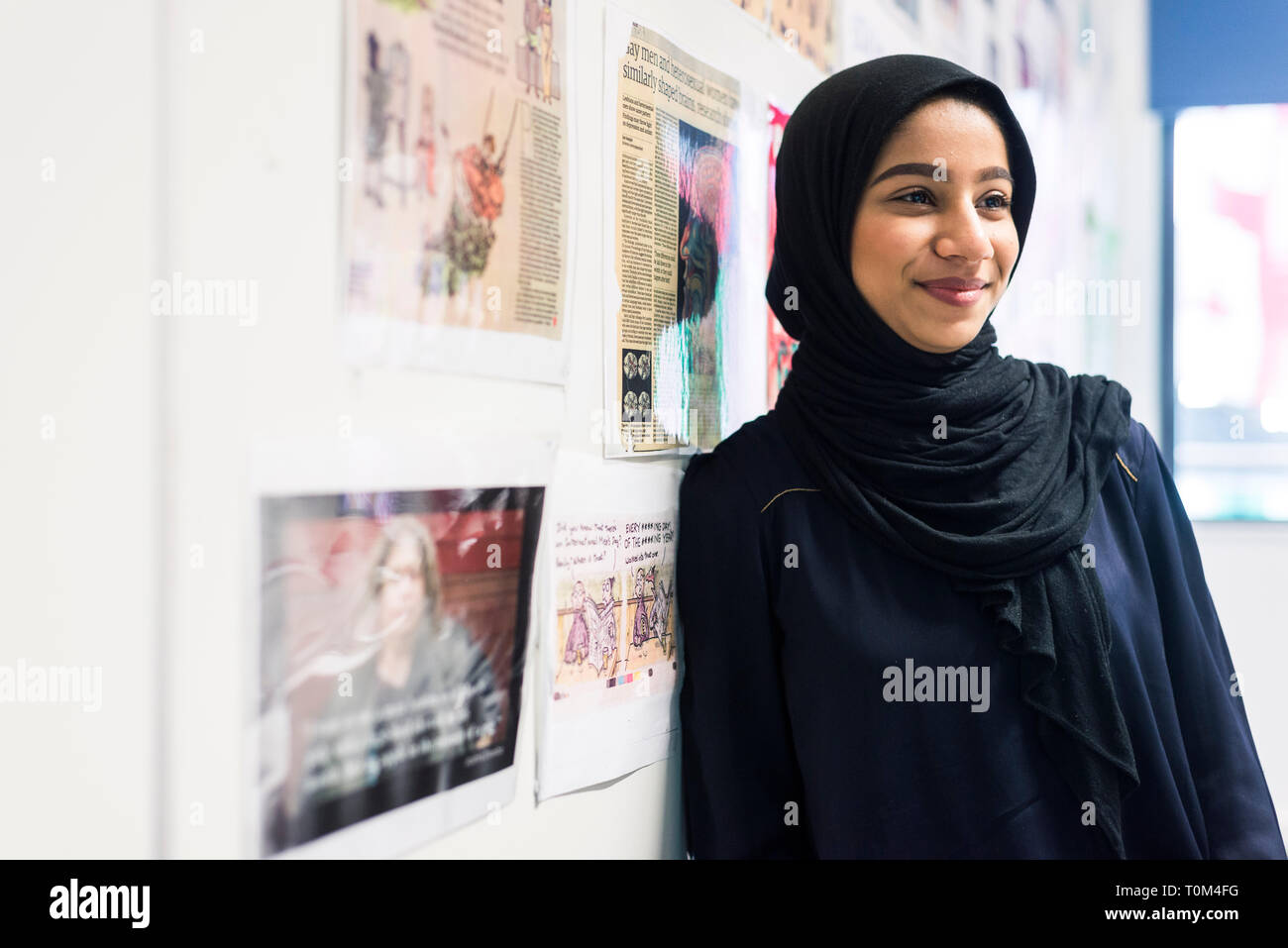 A young Muslim international student stands in the hallways on campus ...