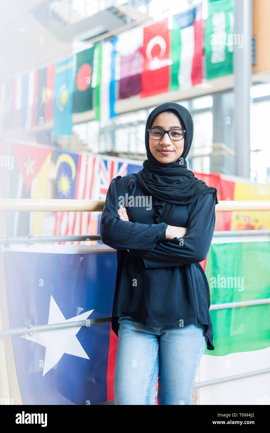 A young Muslim international student stands in the hallways on campus ...