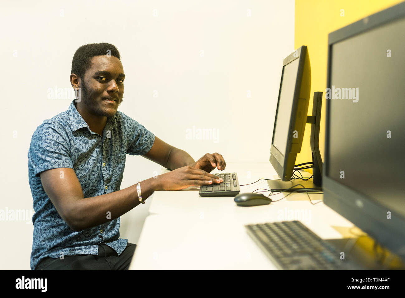 A young black man sits at a desk in the computer room of a college ...
