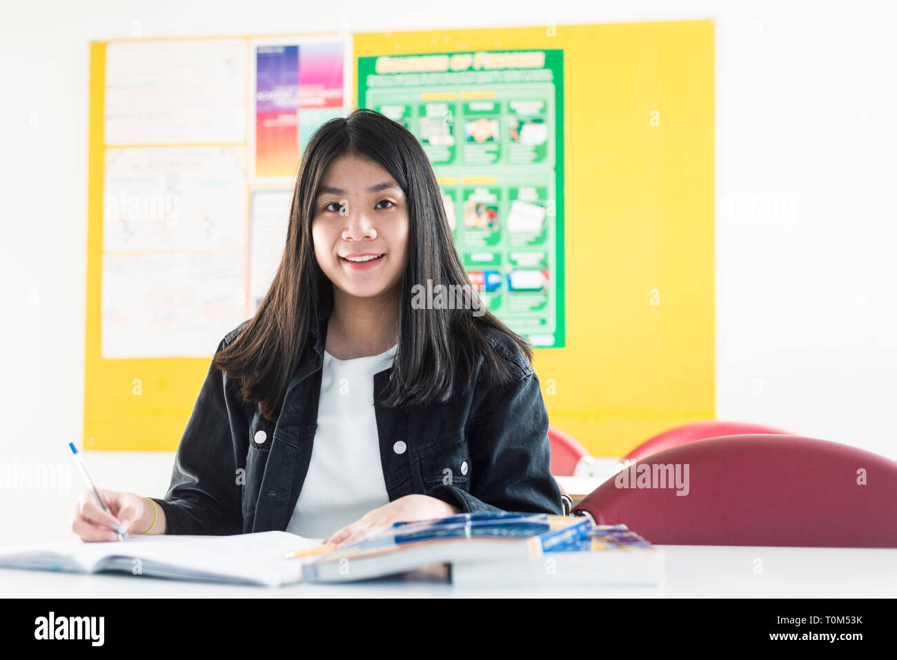 A young international Asian student sits at a desk in a classroom ...
