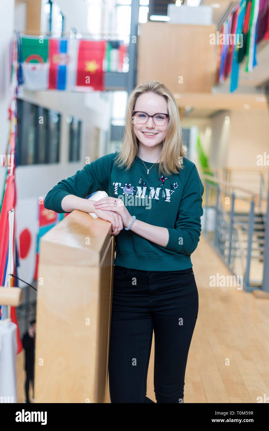 A young international european student stands with the flags on a ...