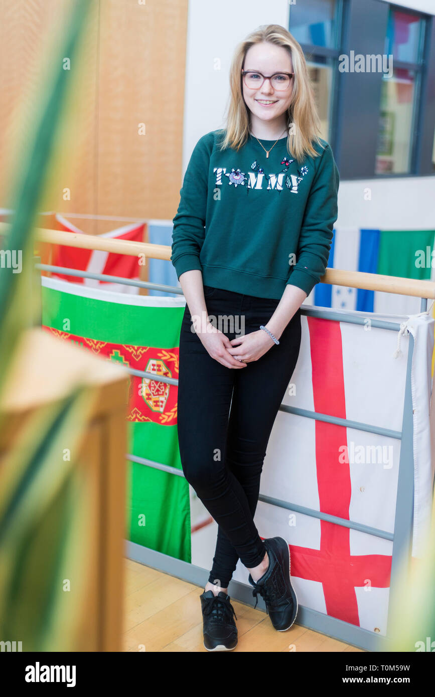 A young international european student stands with the flags on a ...