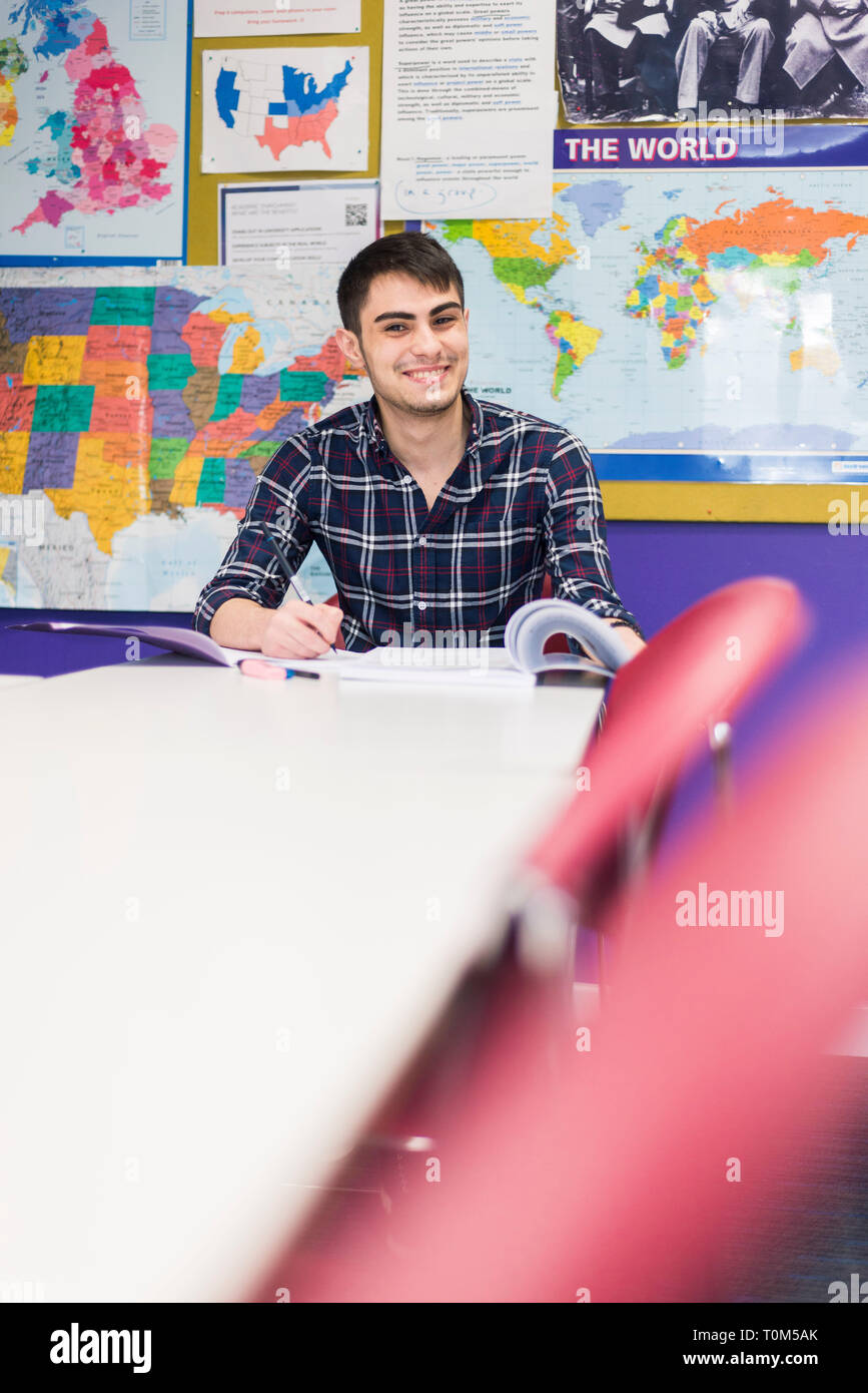 A young middle eastern student sits at a desk during a lesson and ...