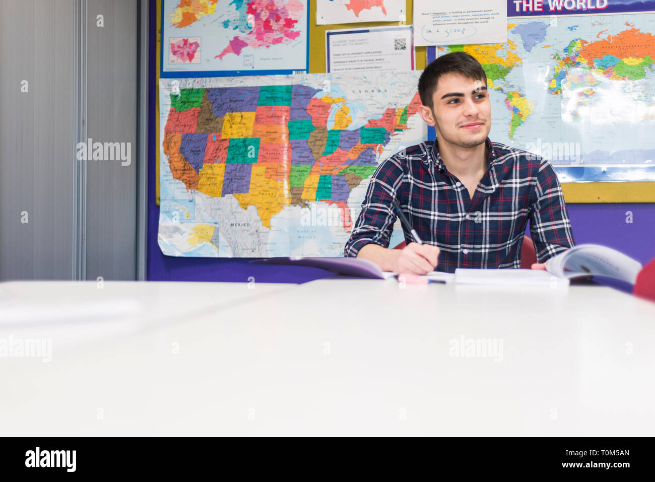 A young middle eastern student sits at a desk during a lesson and ...