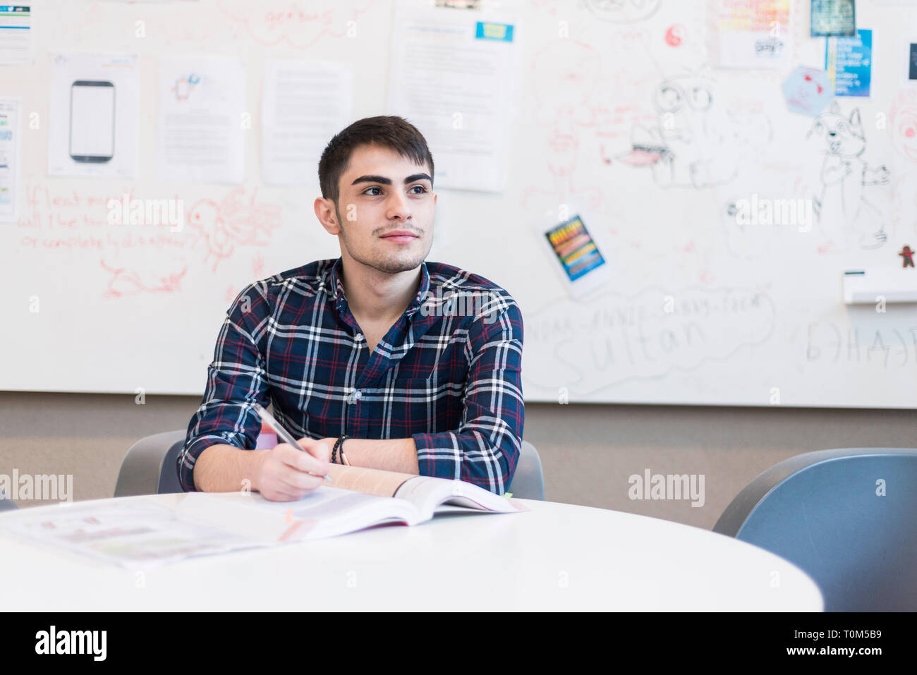 A young middle eastern student sits at a desk during a lesson and ...