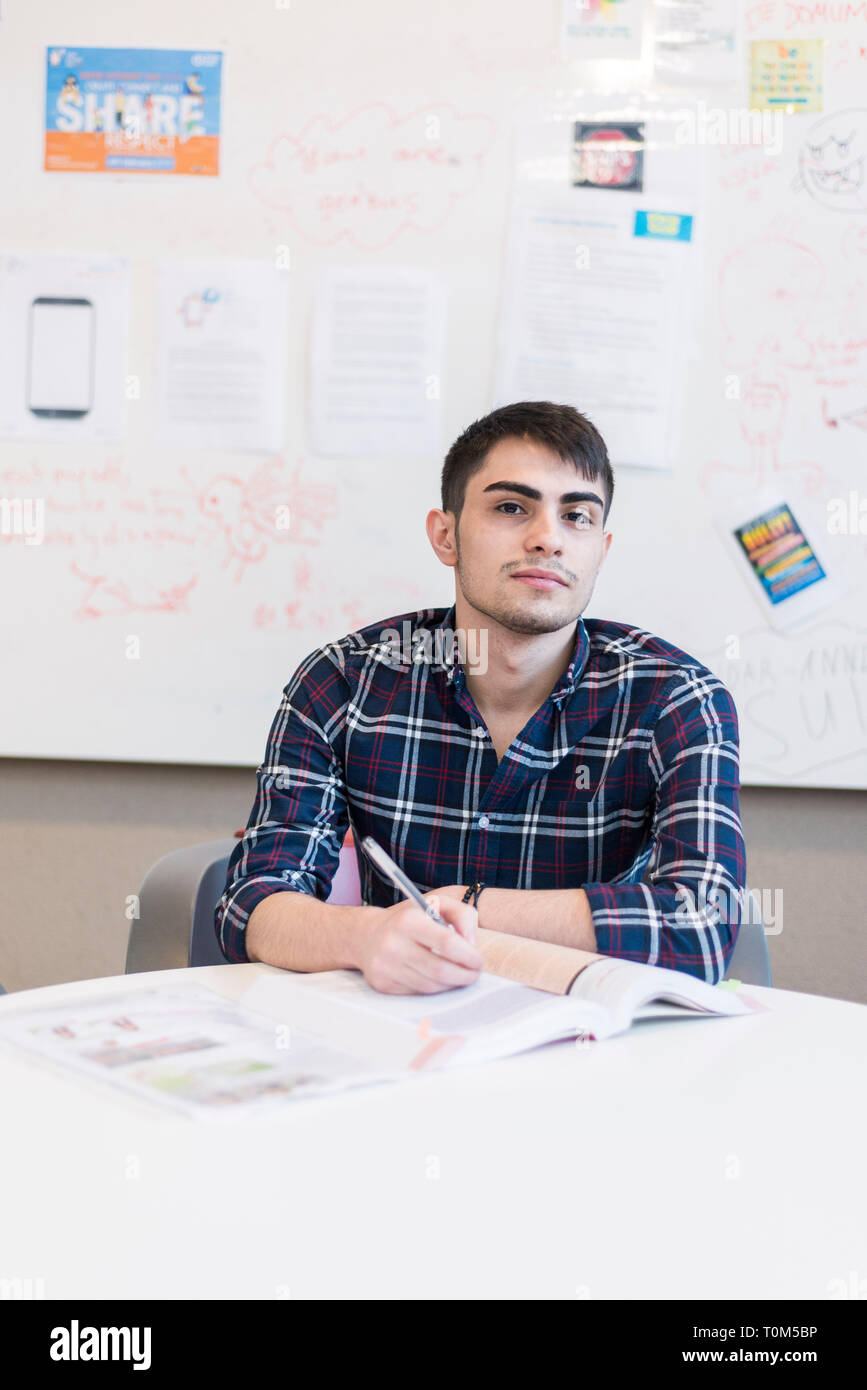 A young middle eastern student sits at a desk during a lesson and ...