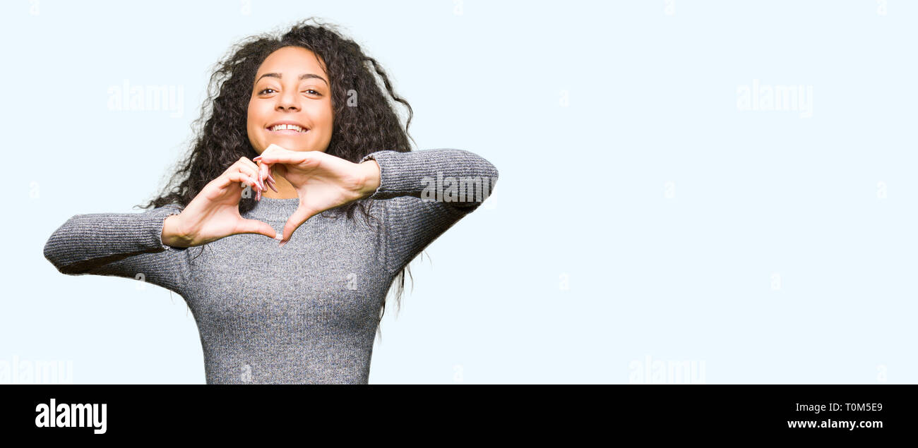 Young beautiful girl with curly hair smiling in love showing heart ...