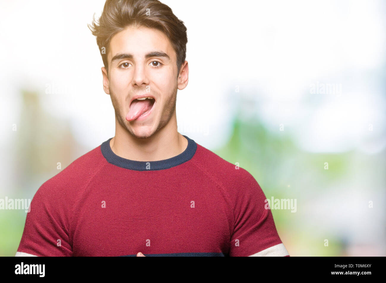 Young handsome man over isolated background sticking tongue out happy ...