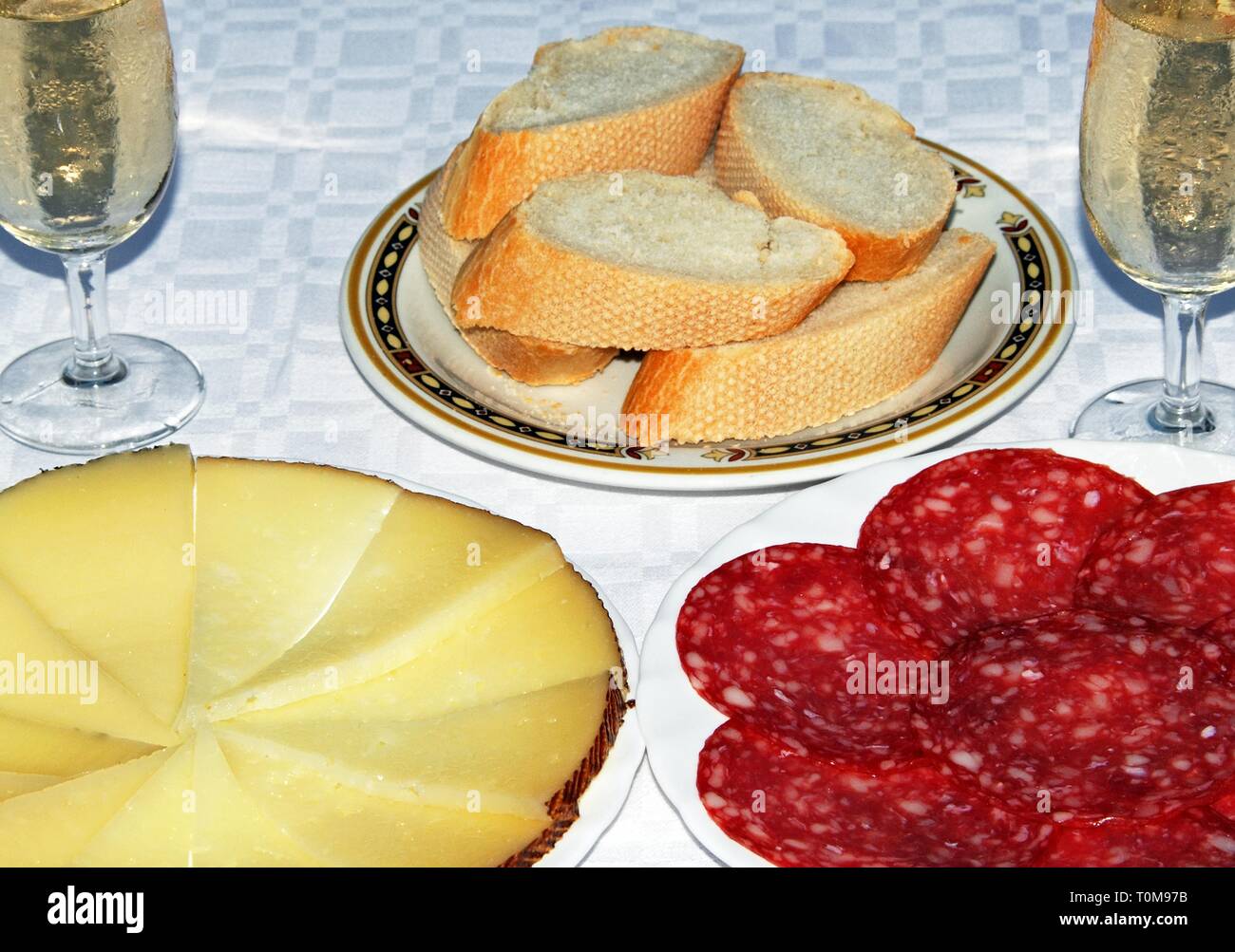 Spanish tapas of Manchego cheese and salami with two glasses of fino ...