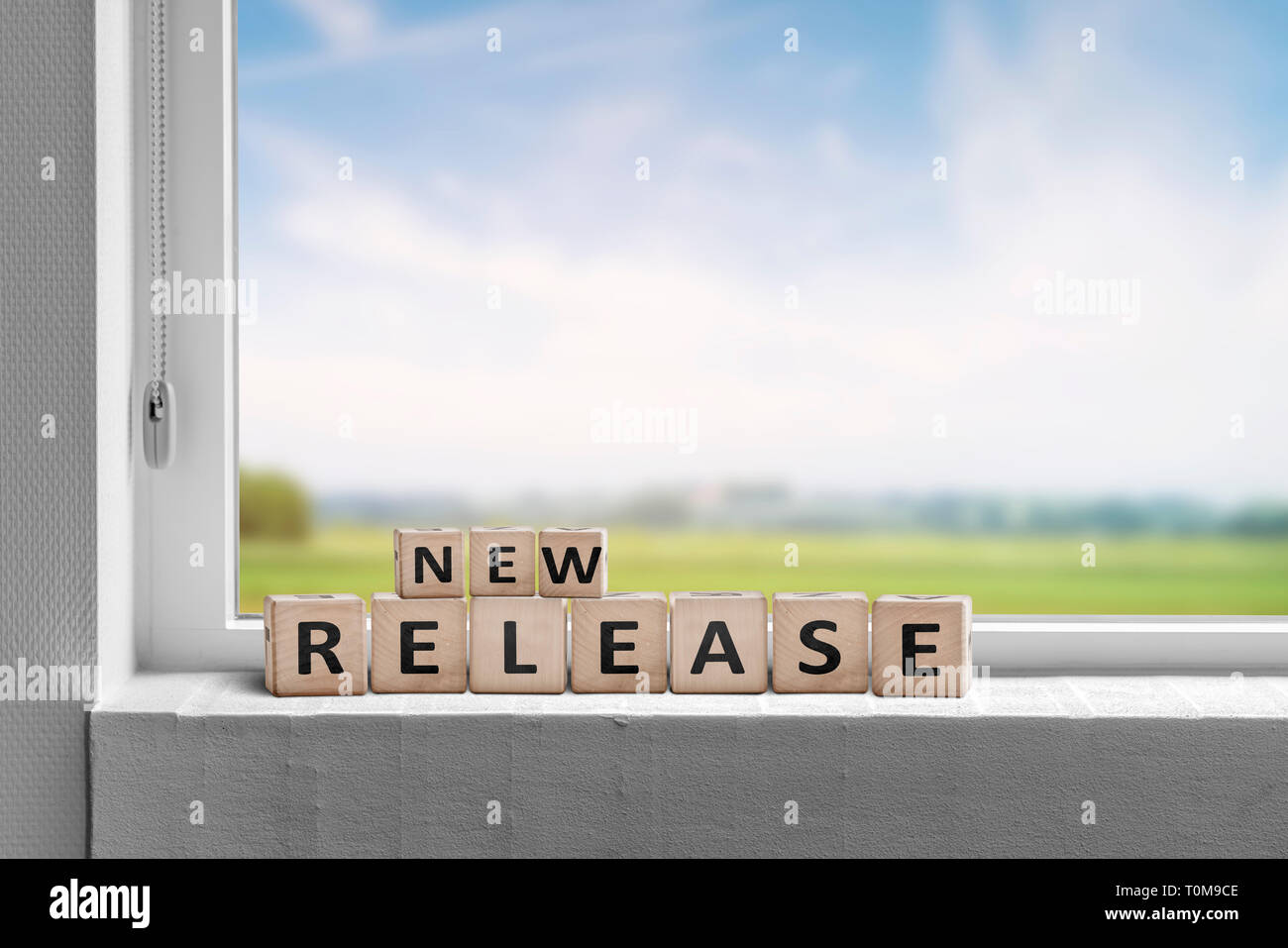 New release sign in a window on a sill with a view to green fields and ...