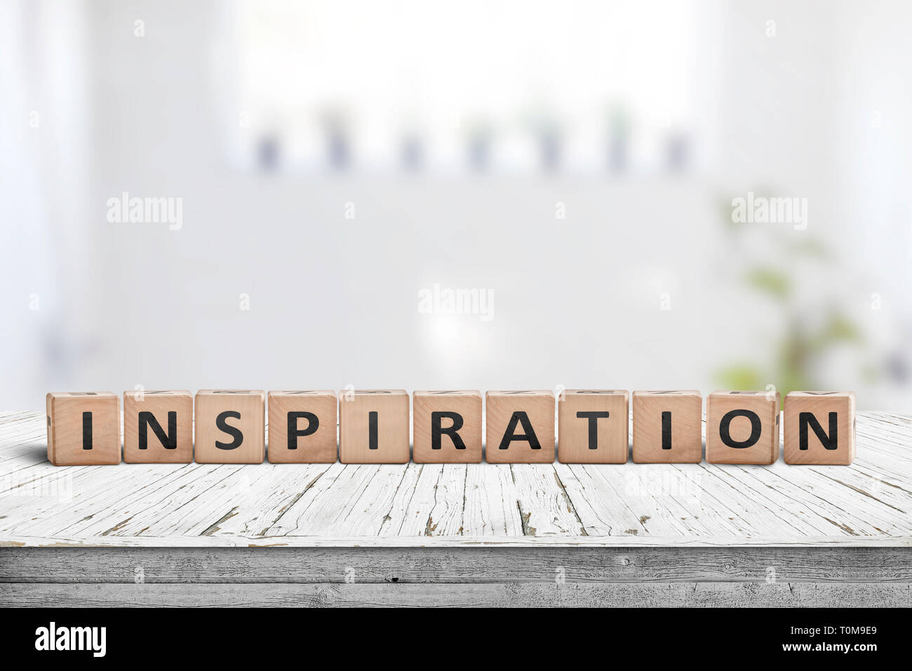 Inspiration sign on a wooden table in a bright room with green plants ...