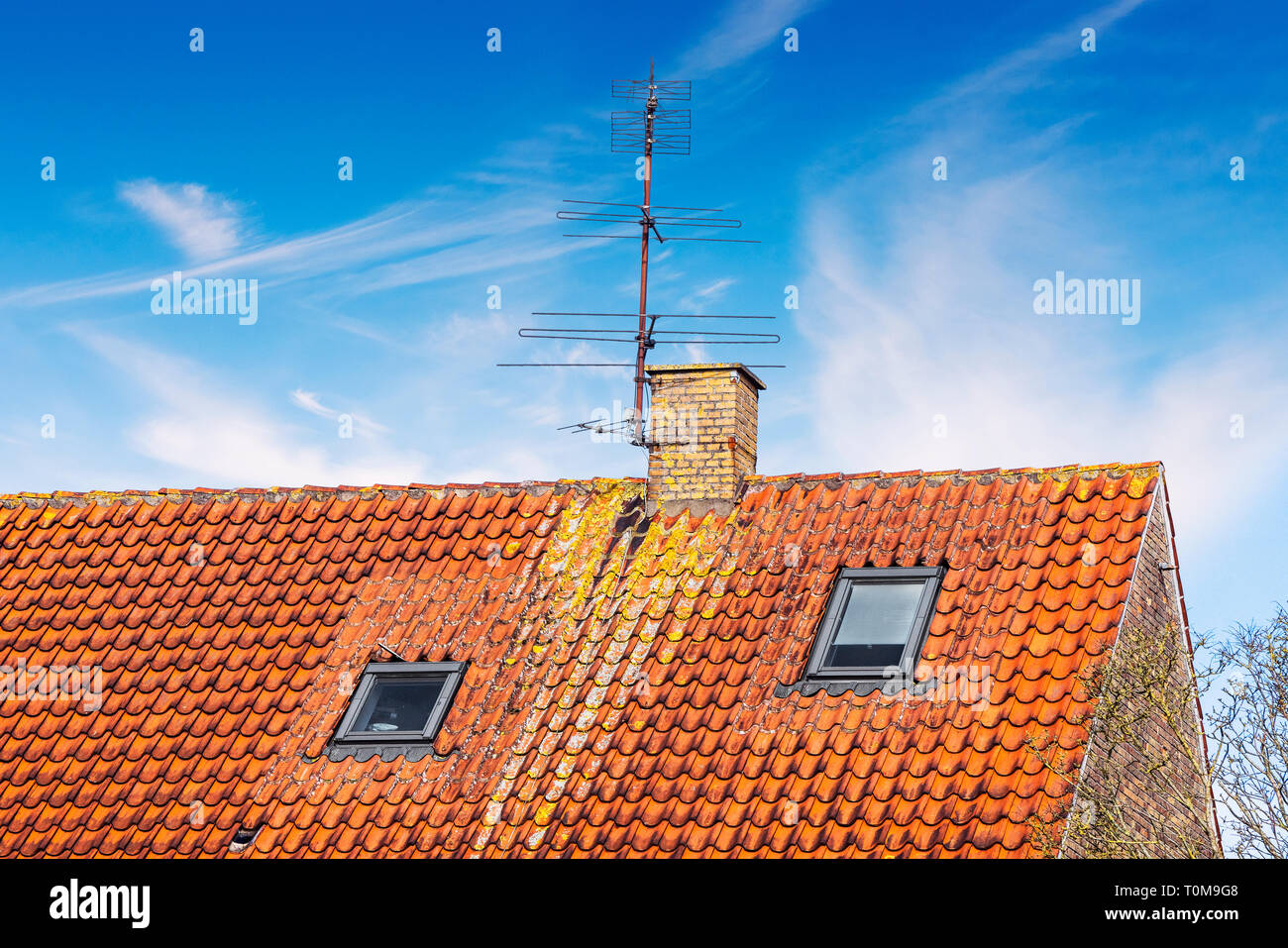 Rooftop with an antenna and a chimney under a blue sky in the summer ...