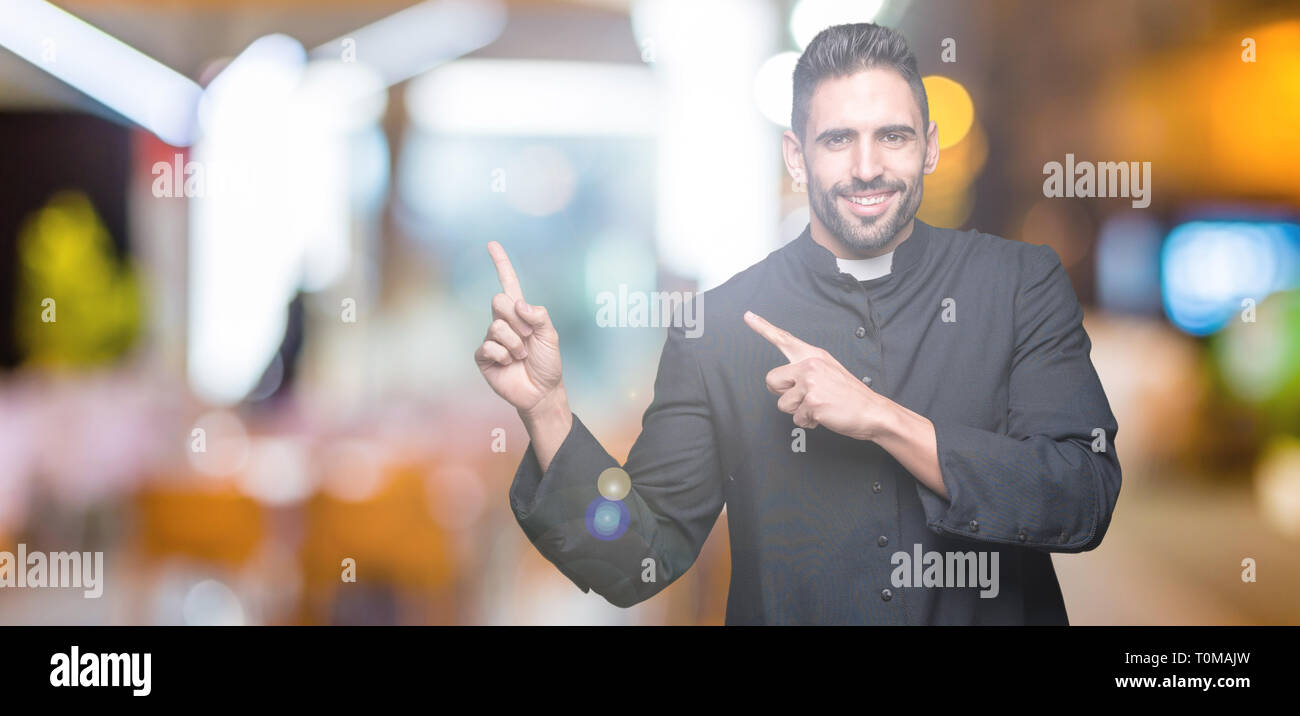 Young Christian priest over isolated background smiling and looking at ...