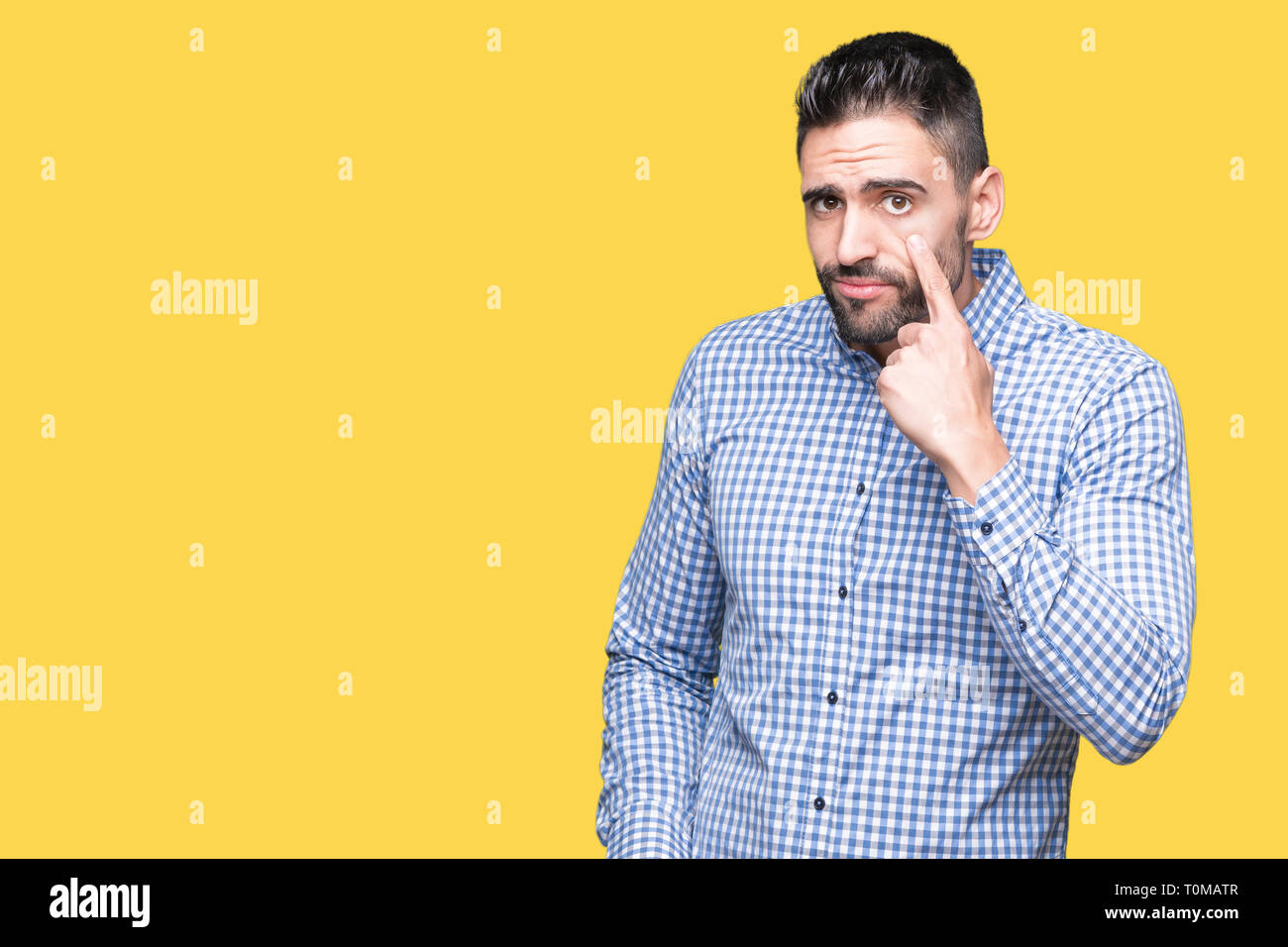 Young handsome man over isolated background Pointing to the eye ...