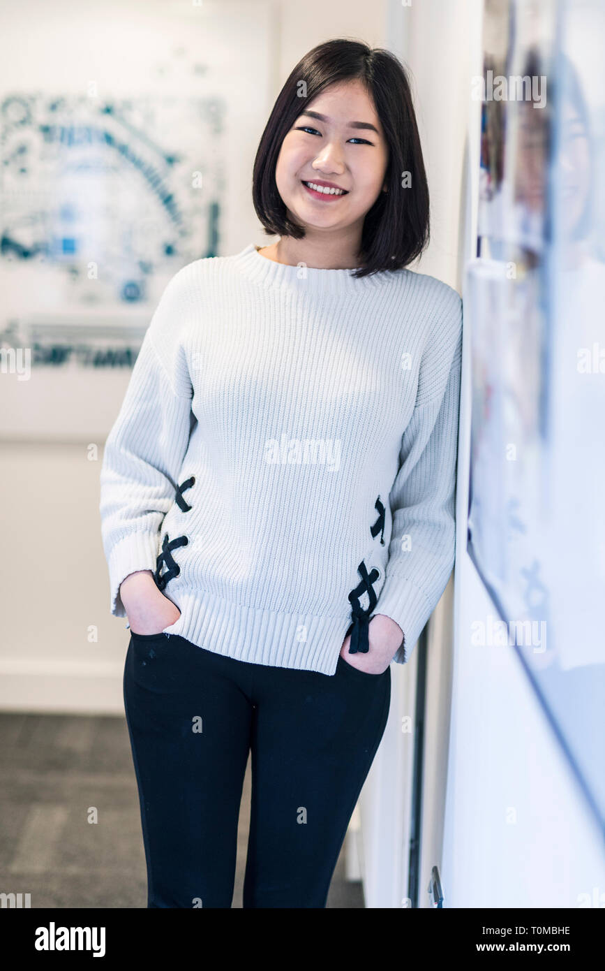 a female asian international student stands in the corridor of a ...