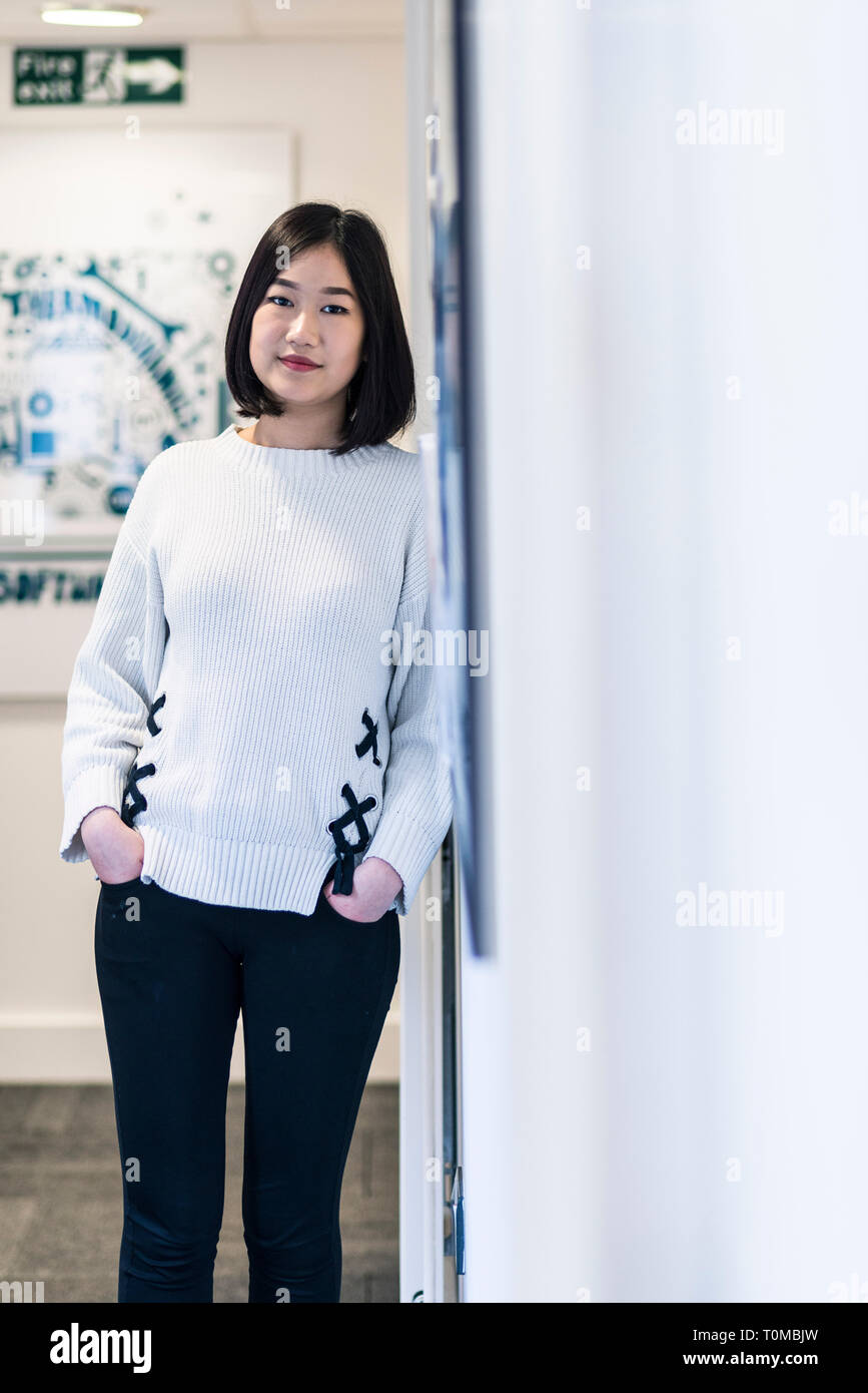 a female asian international student stands in the corridor of a ...