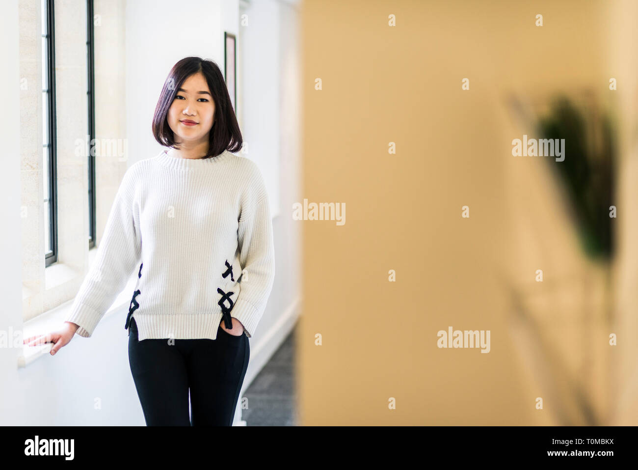 a female asian international student stands in the corridor of a ...