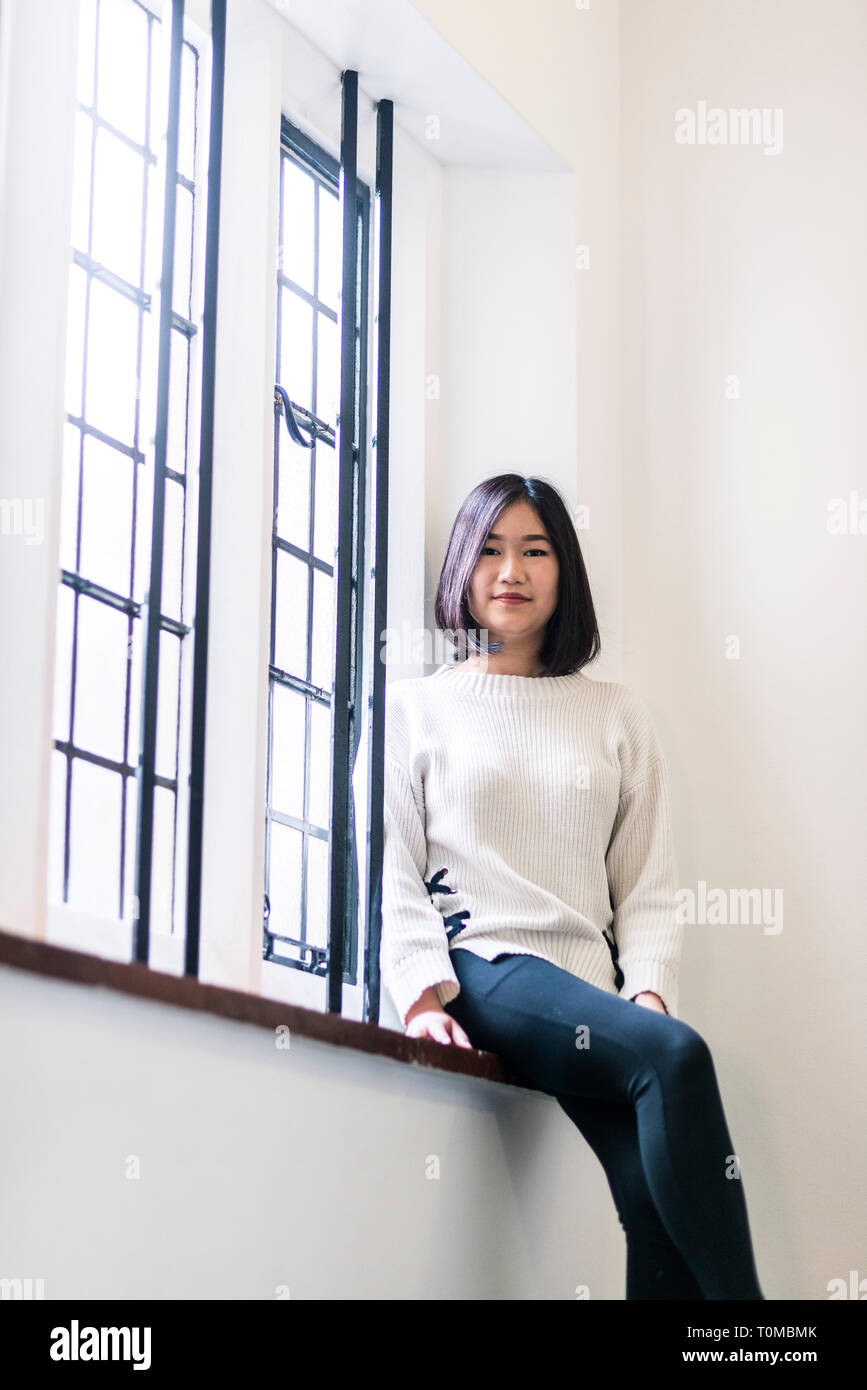a female asian international student stands in the corridor of a ...