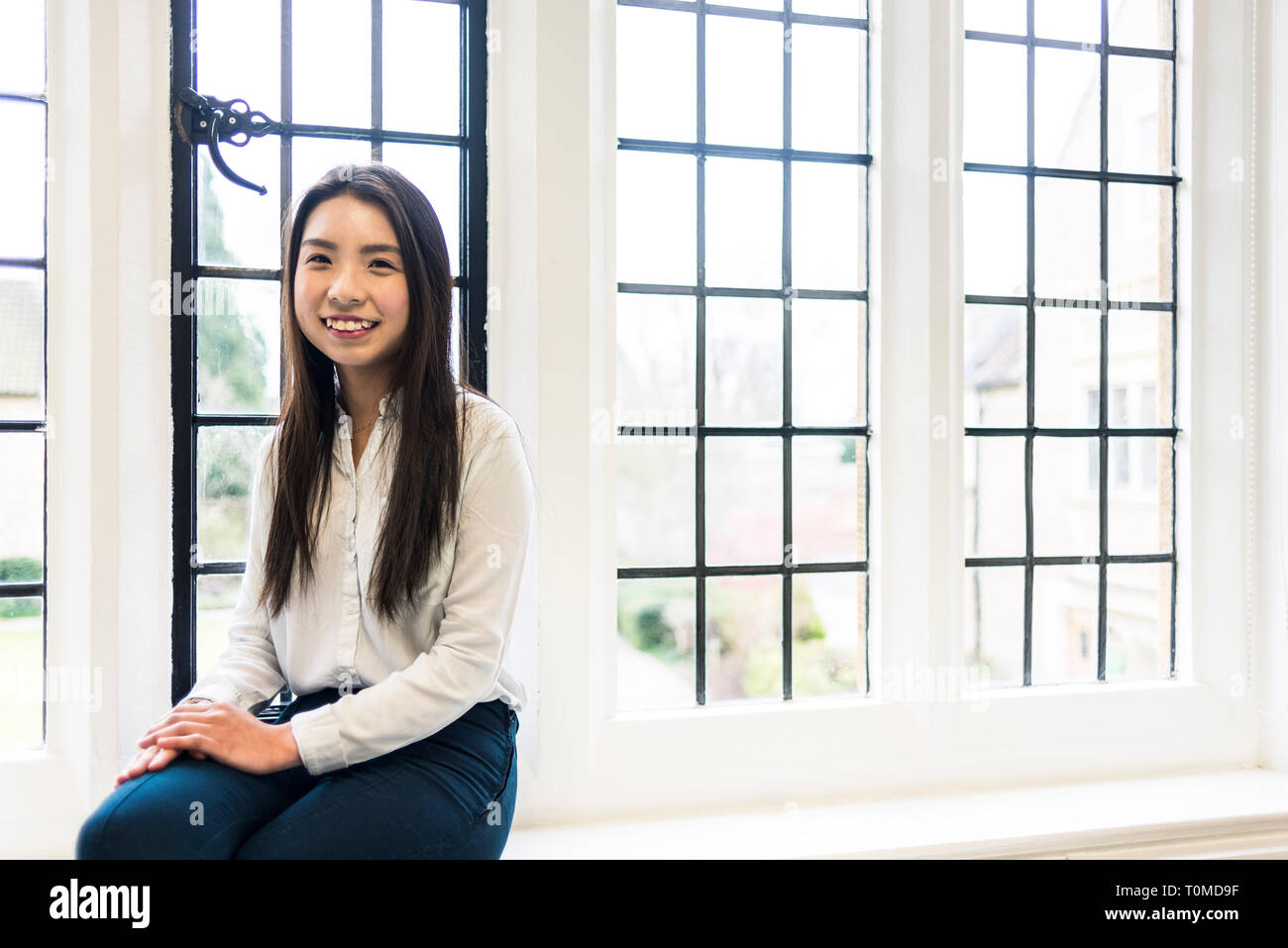 a female asian international student stands in the corridor of a ...
