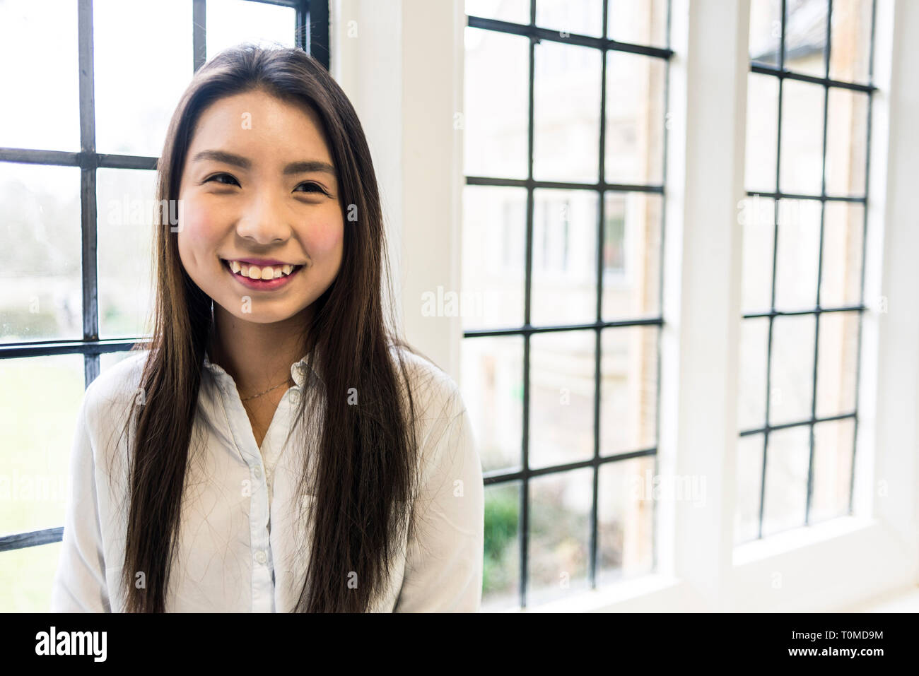 a female asian international student stands in the corridor of a ...