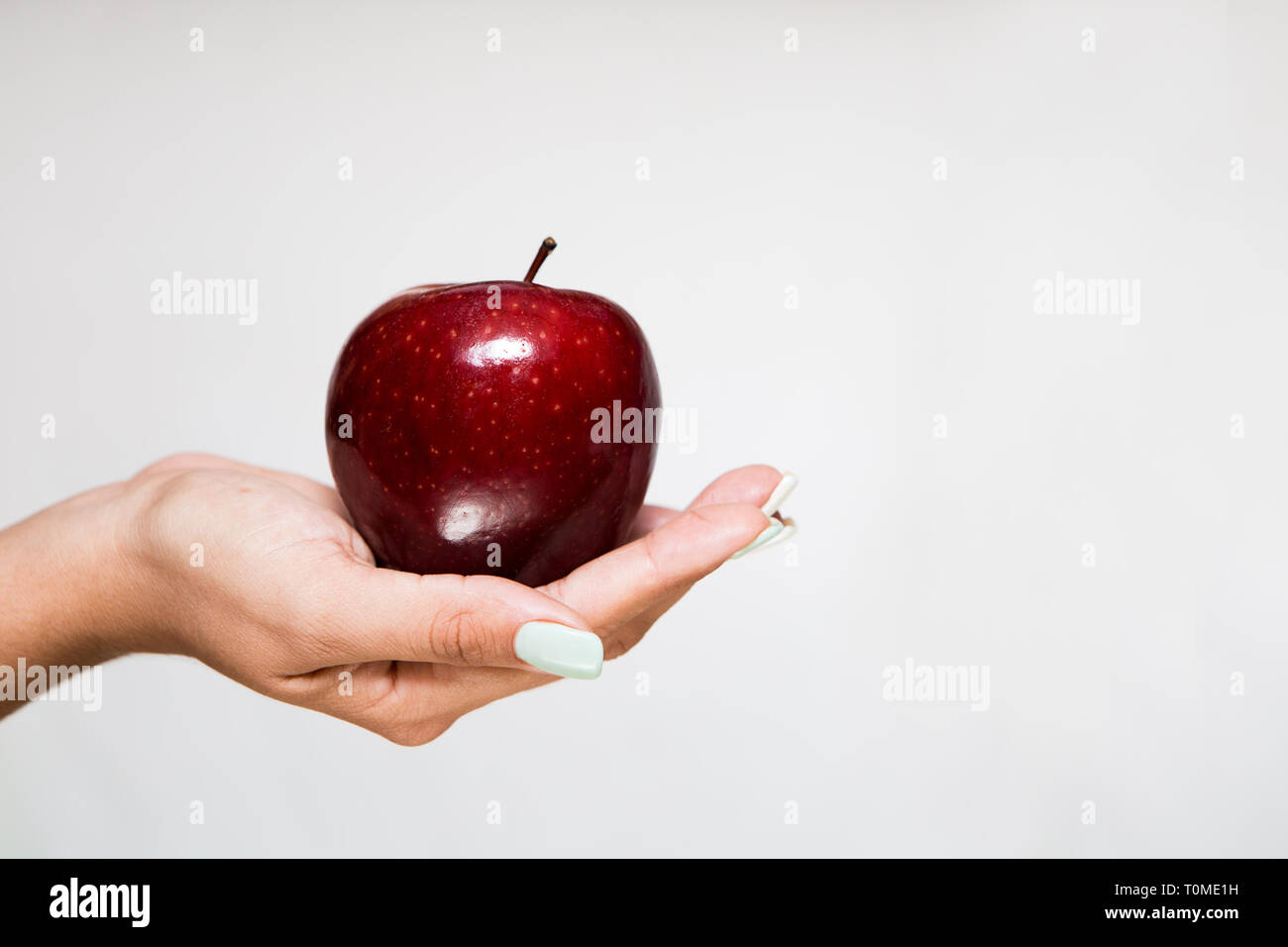 Female hand offering a red apple Stock Photo - Alamy