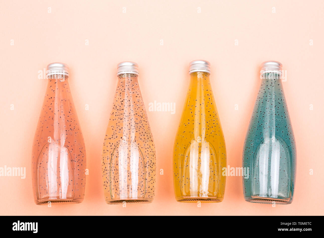 Bottles of different basil seed drinks on pastel pink background. Flat ...