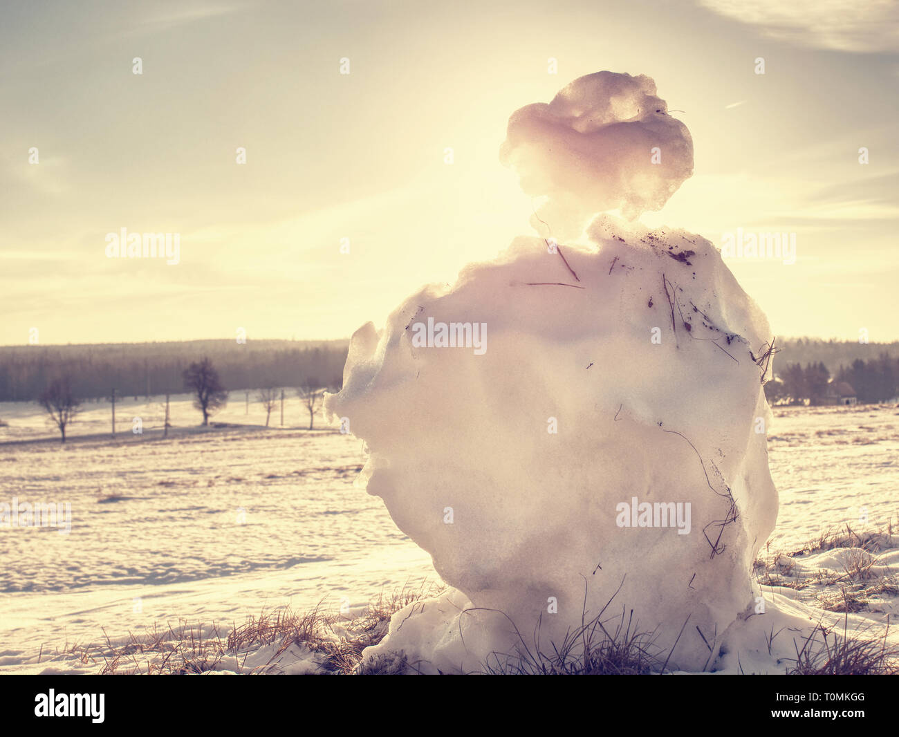 Melting icy snow manin landscape. People walk in winter sunny day ...