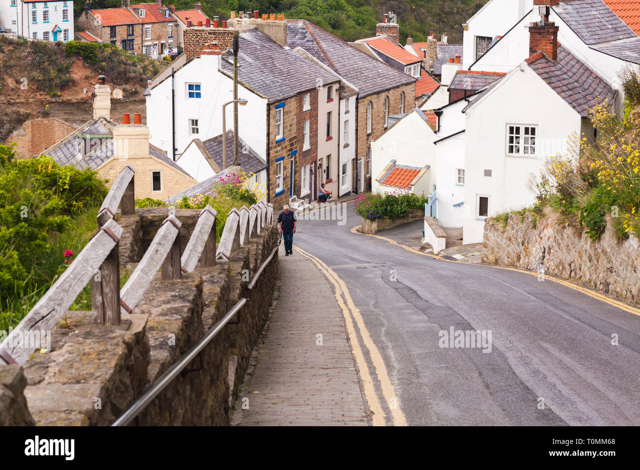 A man walking up the steep bank at Staithes,North Yorkshire,England,UK ...
