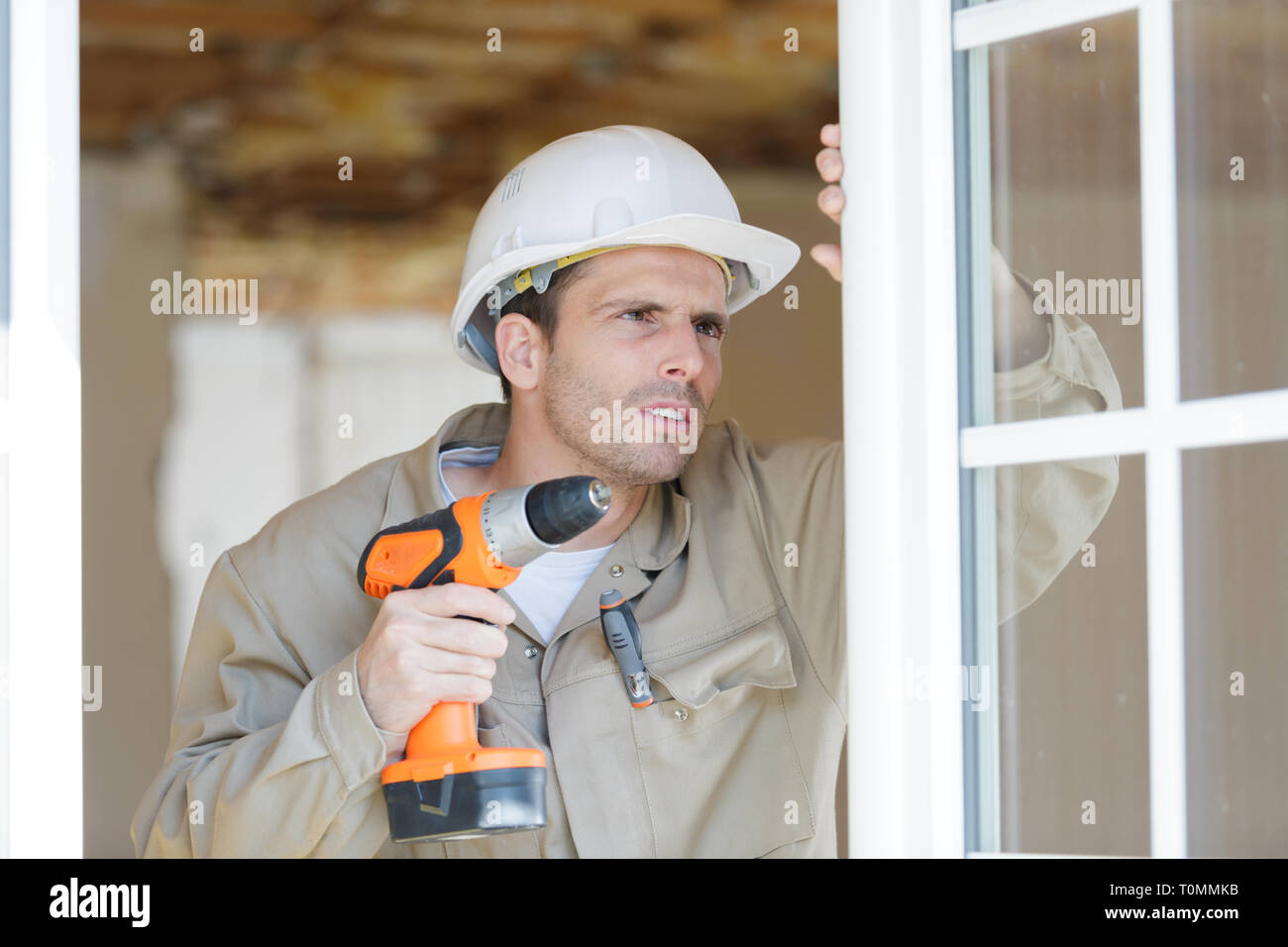 man drilling a hole in a window frame Stock Photo - Alamy
