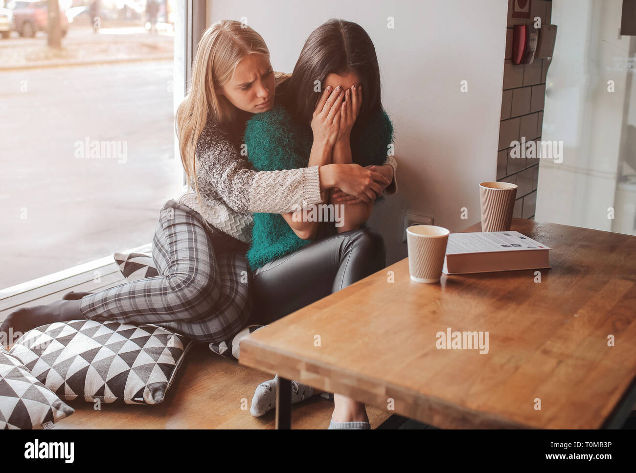 Troubled young girl comforted by her friend. Woman supporting the girl ...