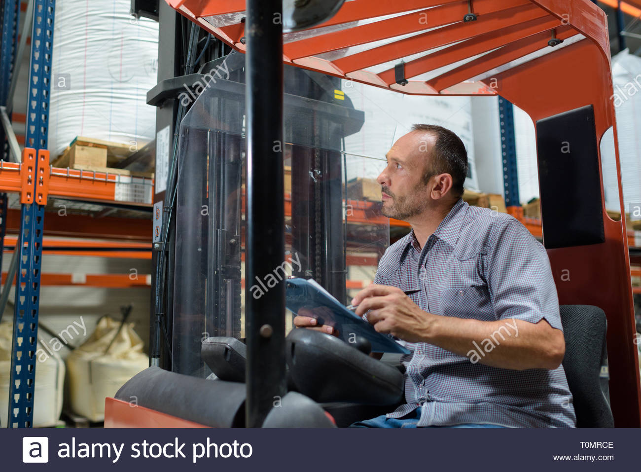 factory worker with clipboard in forklift Stock Photo - Alamy