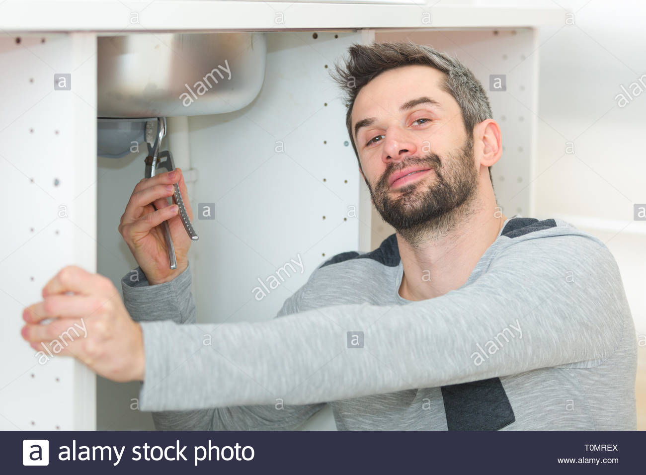 male plumber installing kitchen sink using wrench Stock Photo - Alamy
