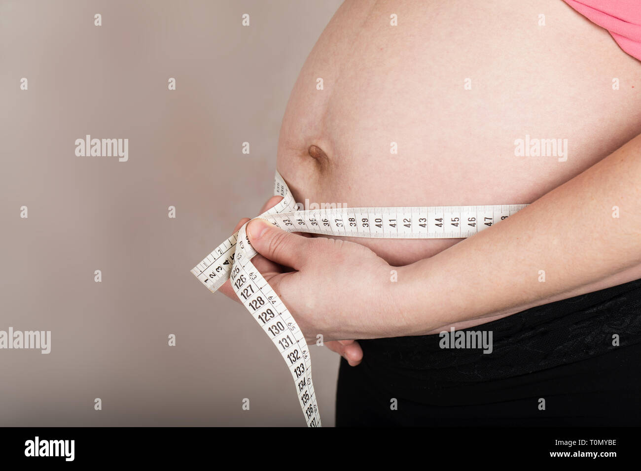 Young pregnant between 30 and 35 years old woman measures her belly ...