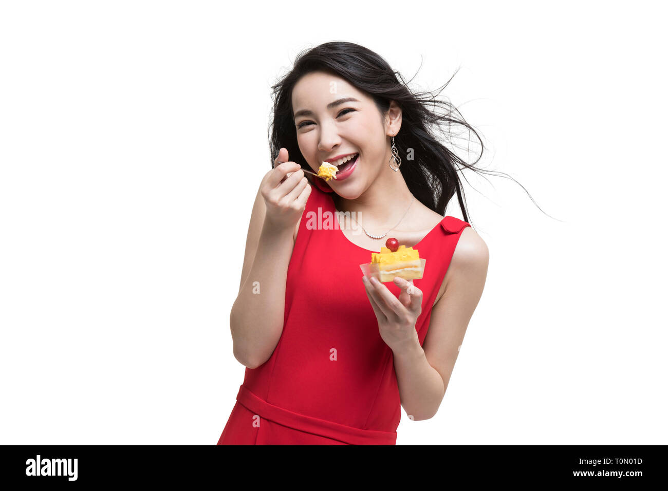 Happy young woman eating cake Stock Photo - Alamy