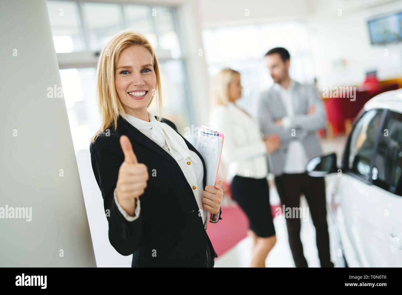 Professional salesperson during work with customer at car dealership ...
