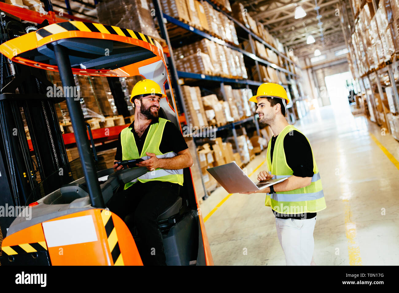 Warehouse workers working together with forklift loader Stock Photo - Alamy