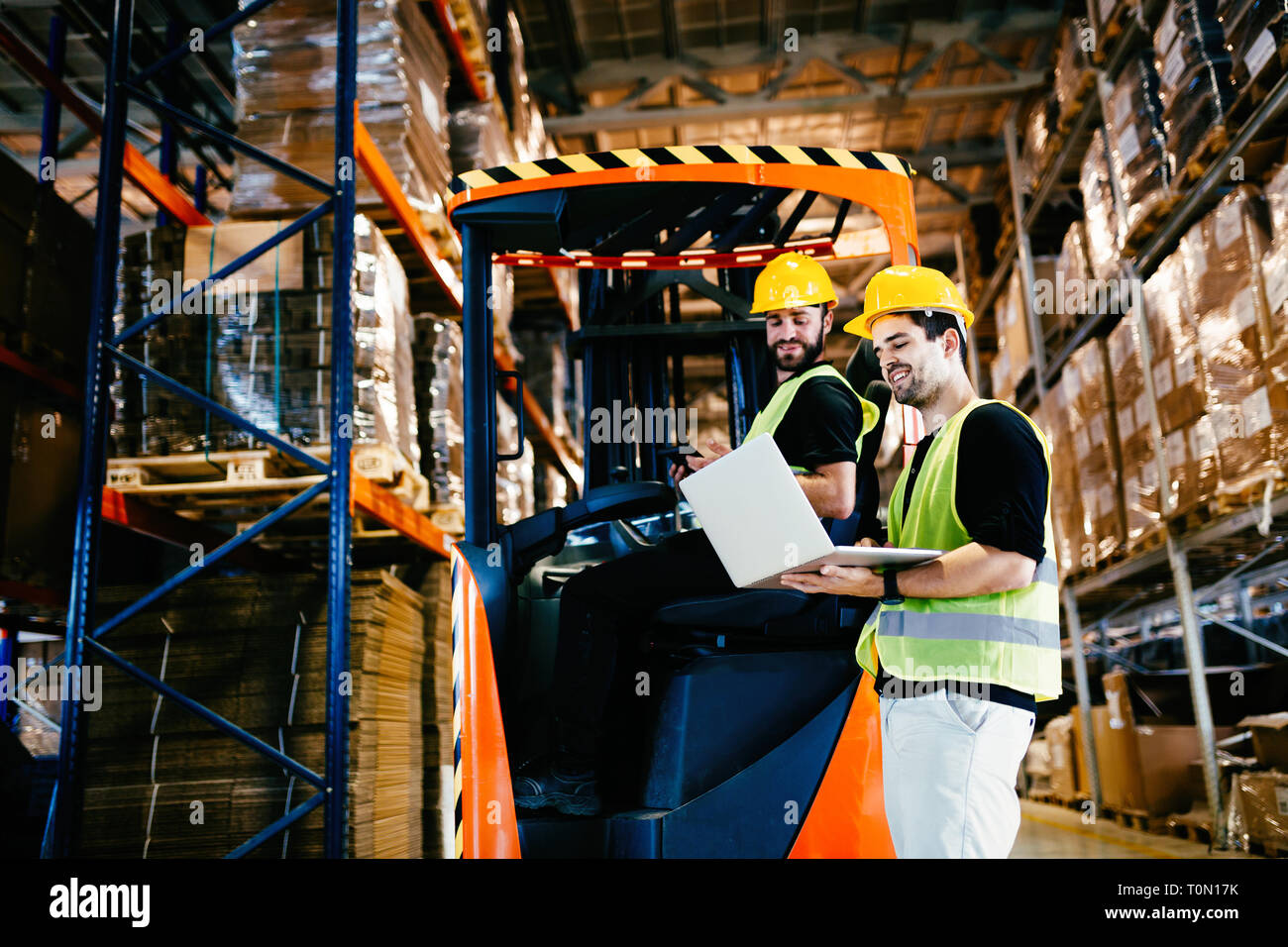 Warehouse workers working together with forklift loader Stock Photo - Alamy