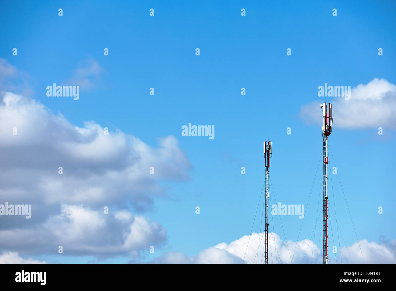 Two cellular phone antennas in the blue sky. Technology on the top of ...