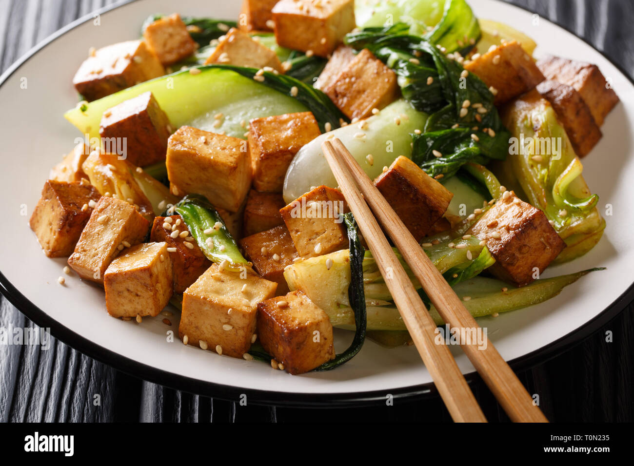 Asian veggie fried tofu with bok cho and sesame close-up on a plate on ...