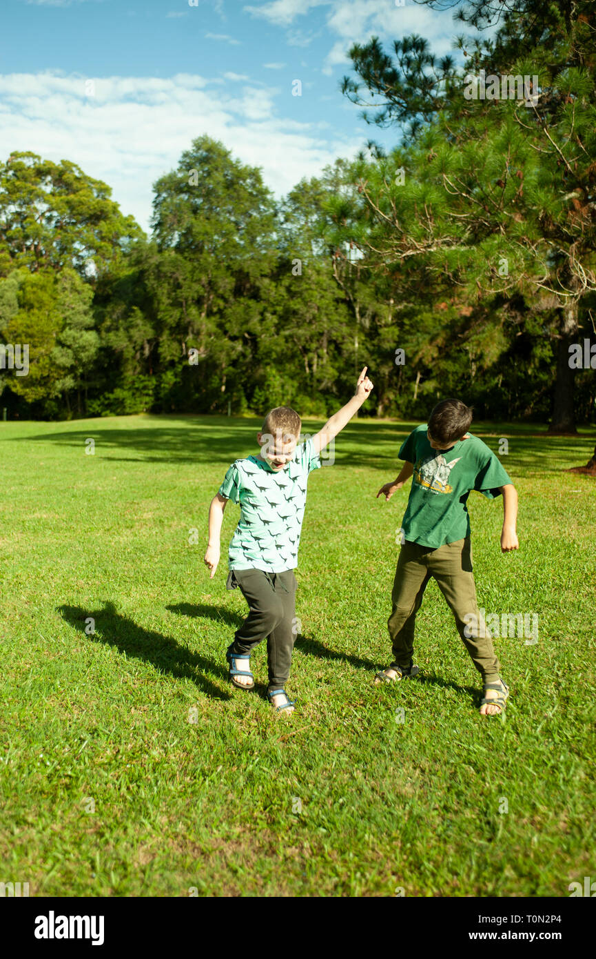 7 and 9 year old young boys dancing on the grass in a nature park Stock ...