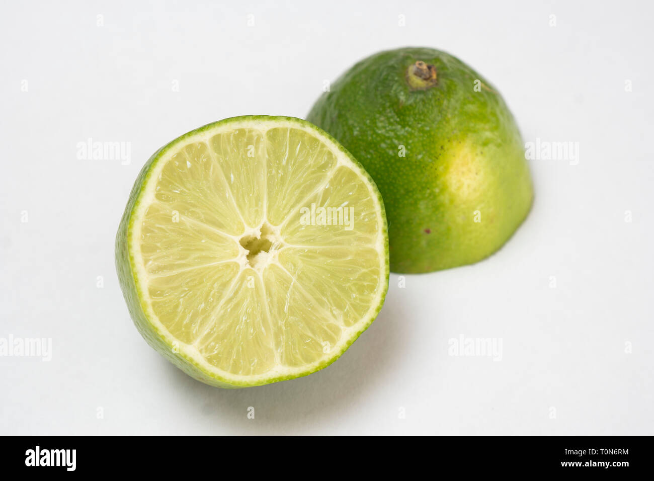 a cutted lime on a plain white table Stock Photo - Alamy