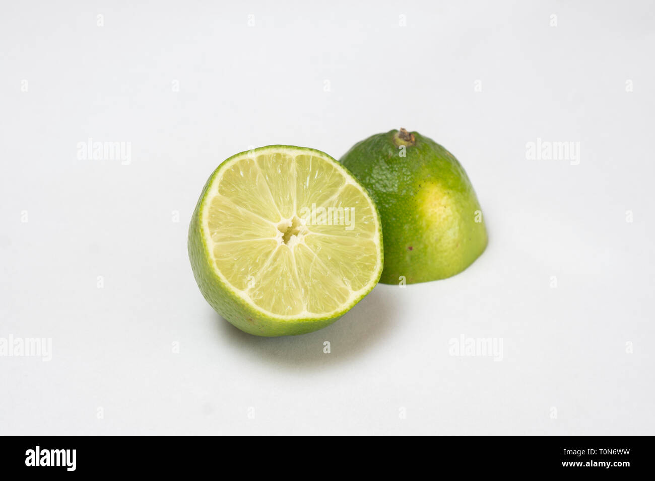 a cutted lime on a plain white table Stock Photo - Alamy