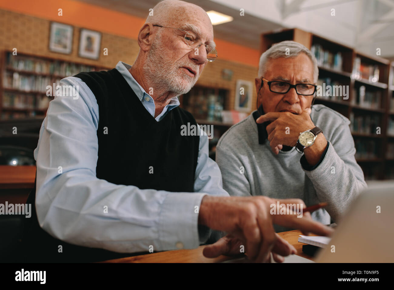 Two elderly gentlemen learning courses on laptop sitting in classroom ...