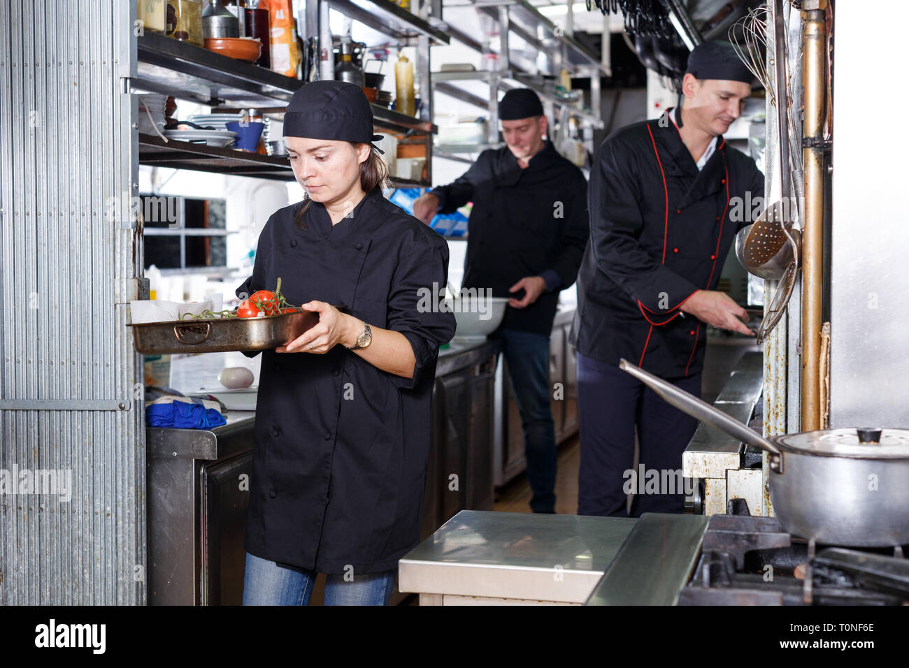 Positive cooks in process of working in kitchen of restaurant Stock ...