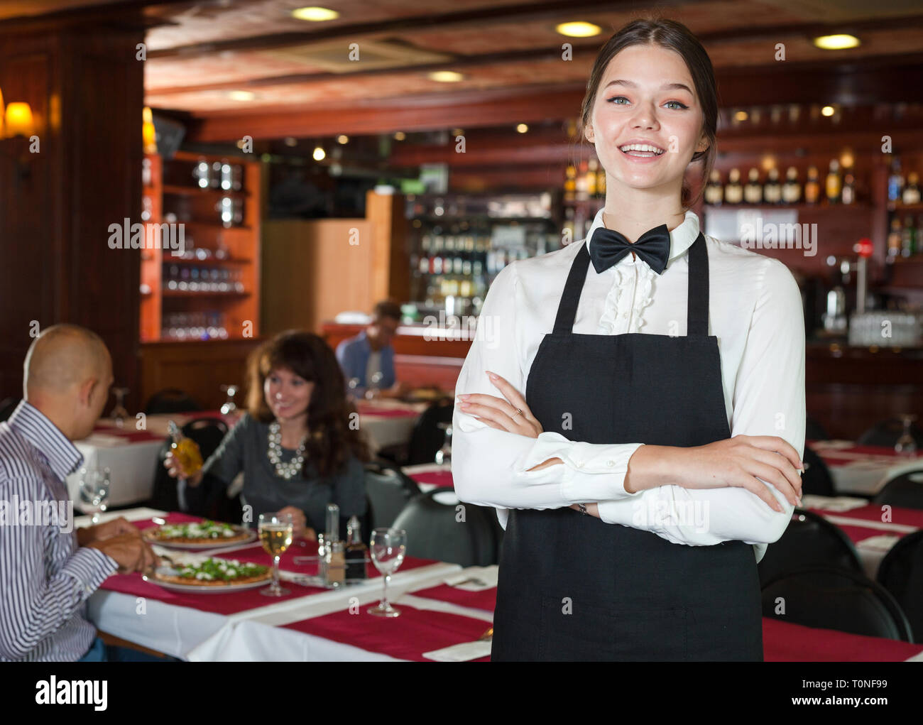 Attractive young waitress meeting guests in restaurant hall Stock Photo ...